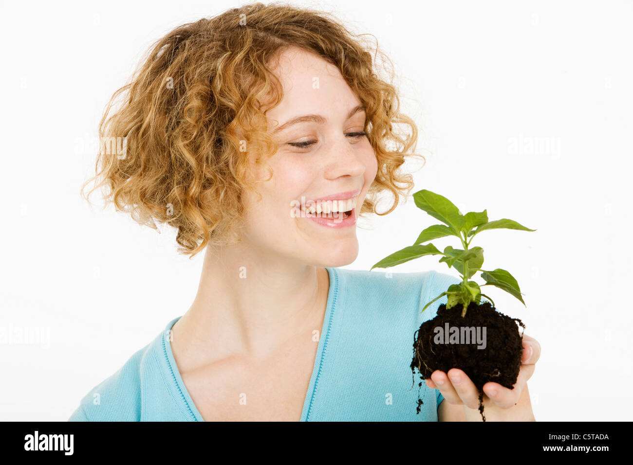 Young woman holding plant, smilling, portrait Stock Photo - Alamy