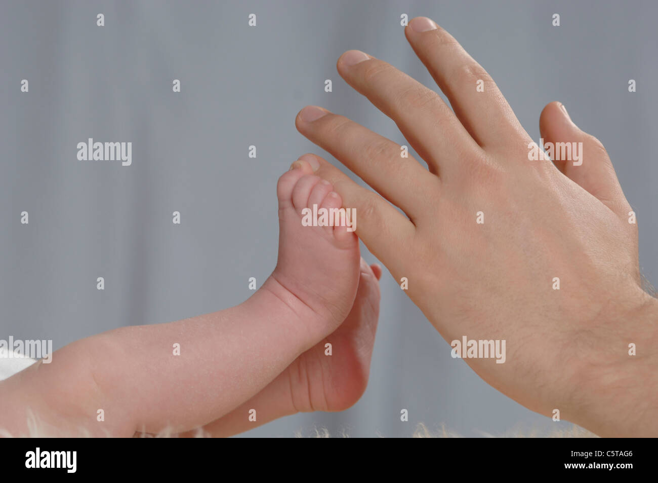 Germany, Bavaria, Munich, Hand touching baby boy's feet (3 weeks ...