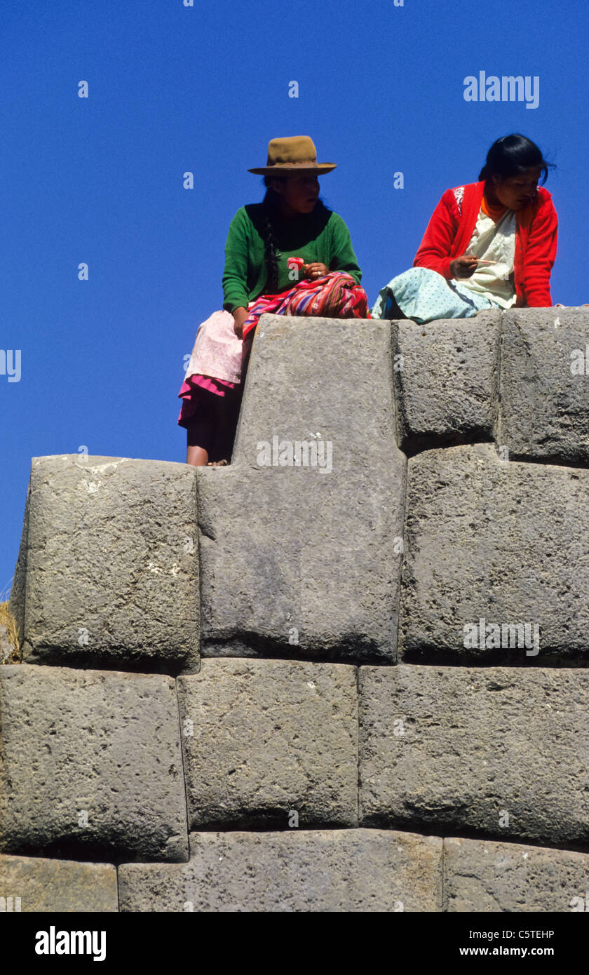 Two Inka girls sitting on the top of the Sacsayhuaman ruin granite ...