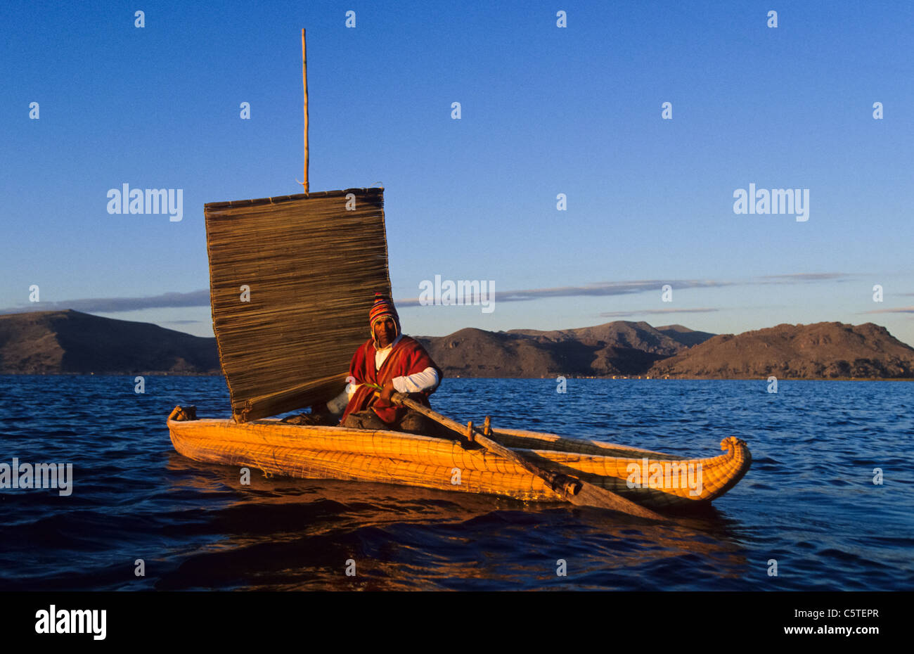 Uros indian man in papyros boat at sunrise in Lake Titicaca Stock Photo ...