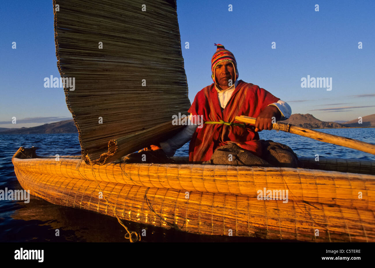 Uros indian man in papyros boat at sunrise in Lake Titicaca Stock Photo ...