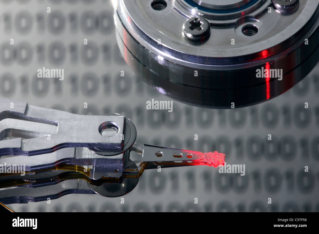 Computer hard drive, opened, writing/reading head and hard disk. Binary code numbers are ...