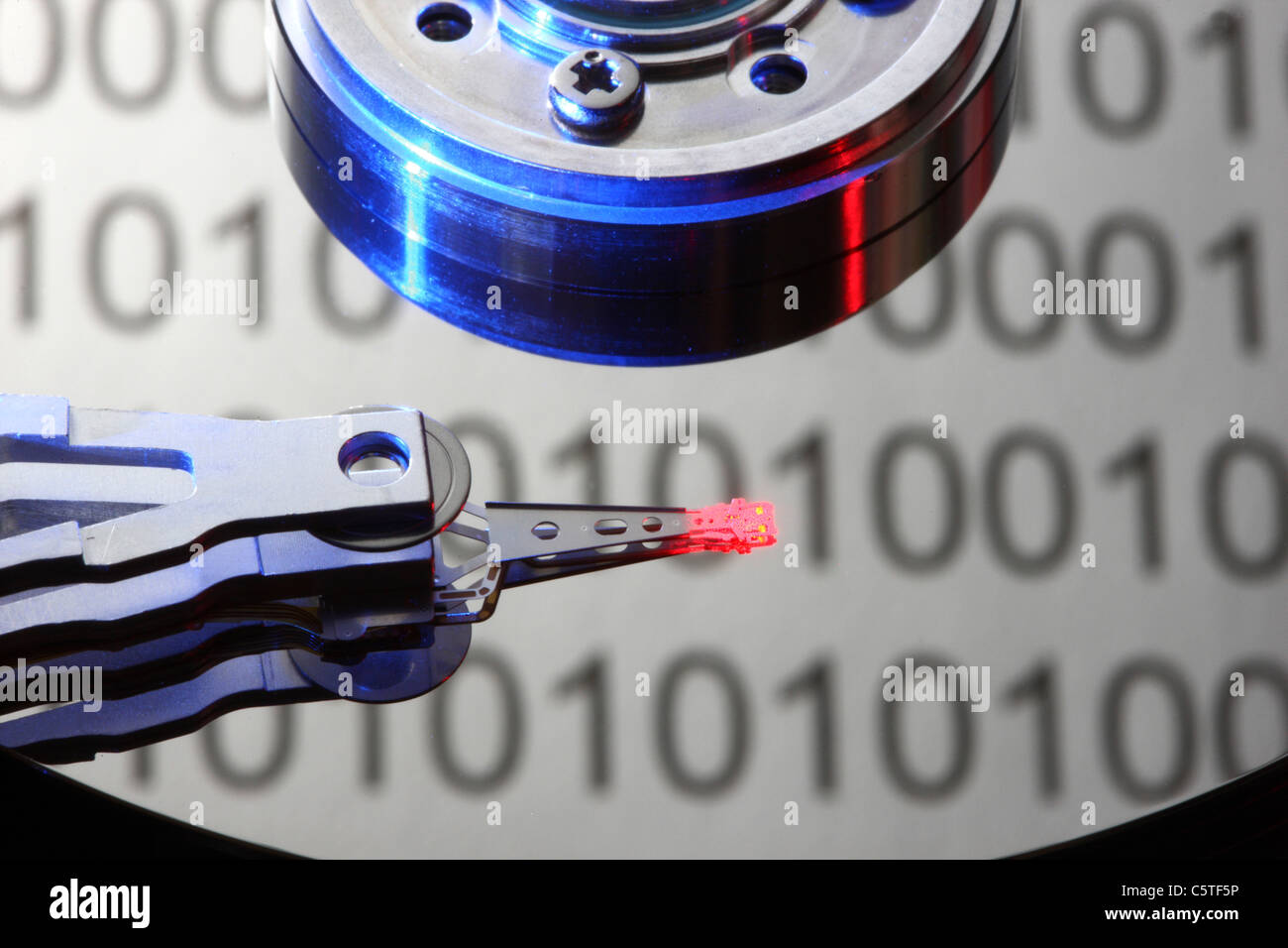 Computer hard drive, opened, writing/reading head and hard disk. Binary code numbers are ...