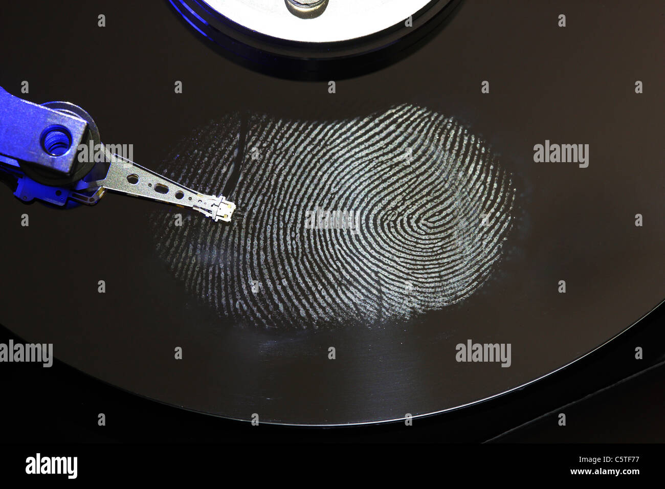 Computer hard drive, opened with writing/reading head and hard disc. Fingerprint on hard disk ...