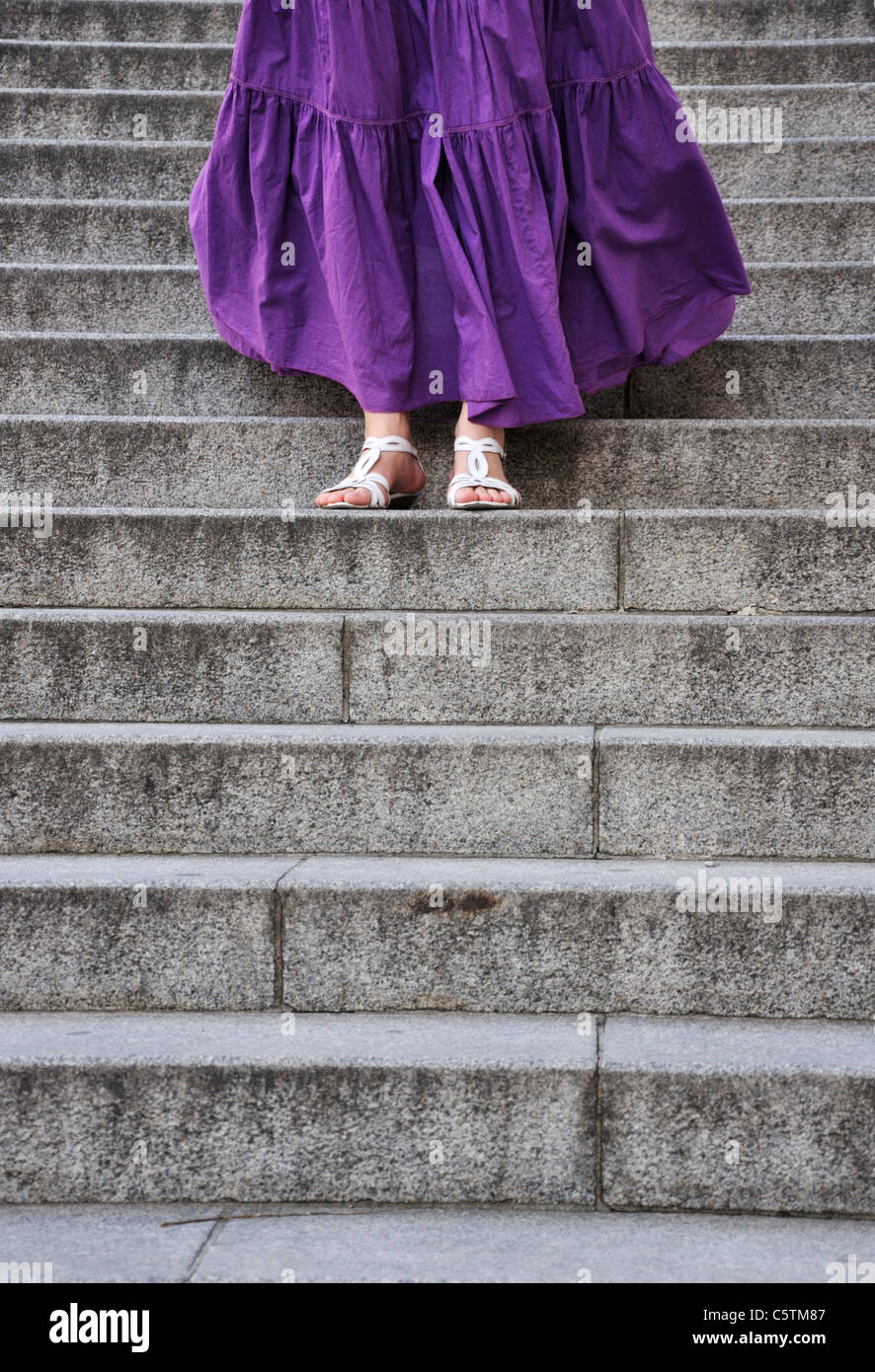 Young woman wearing purple dress standing on steps Stock Photo - Alamy