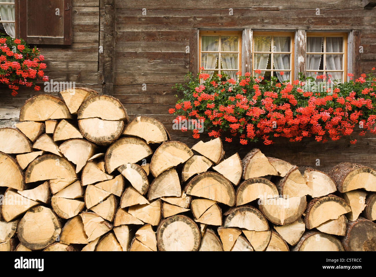 Switzerland, Stack of logs in front of block house Stock Photo - Alamy
