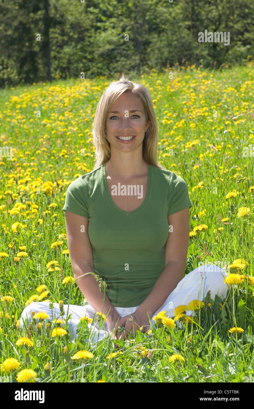 Austria, Salzburger Land, Young woman sitting in meadow, smiling Stock ...