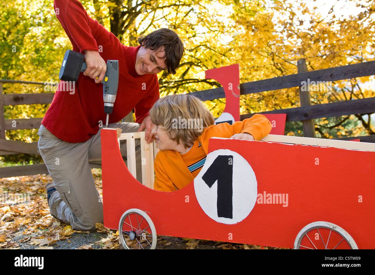 Austria, Salzburger Land, Young man fixing soapbox car, boy (12-13 ...