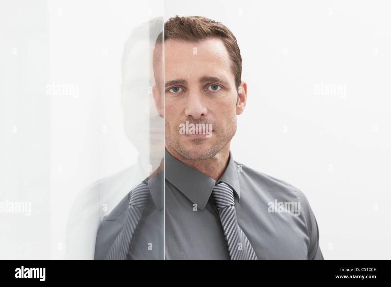 Germany, Cologne, Businessman standing next glass door, portrait Stock ...