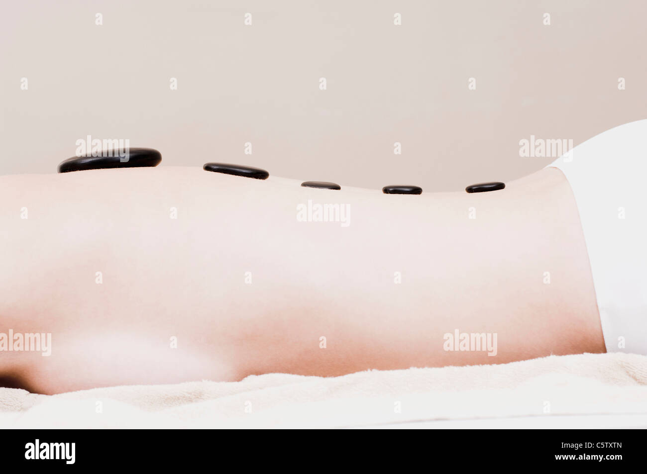 Person receiving hot stone treatment, side view, mid section Stock ...