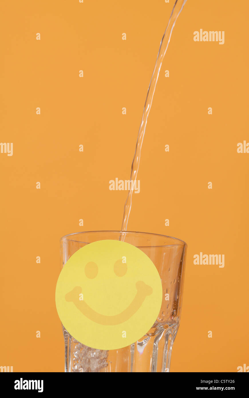 Water being poured into glass, Smiley in foreground Stock Photo - Alamy