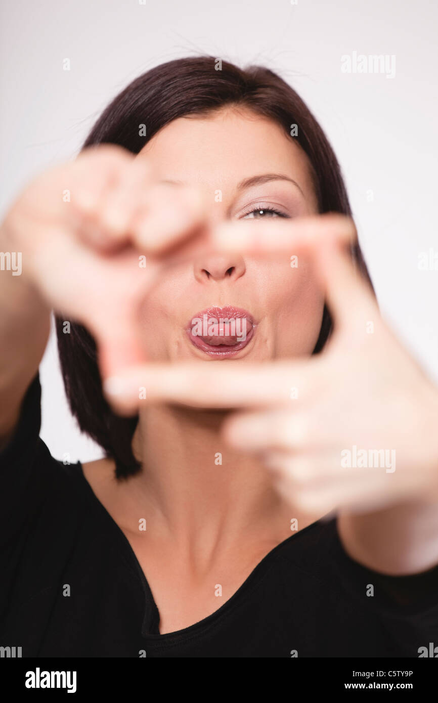 Close up of mid adult woman showing hand sign against white background ...
