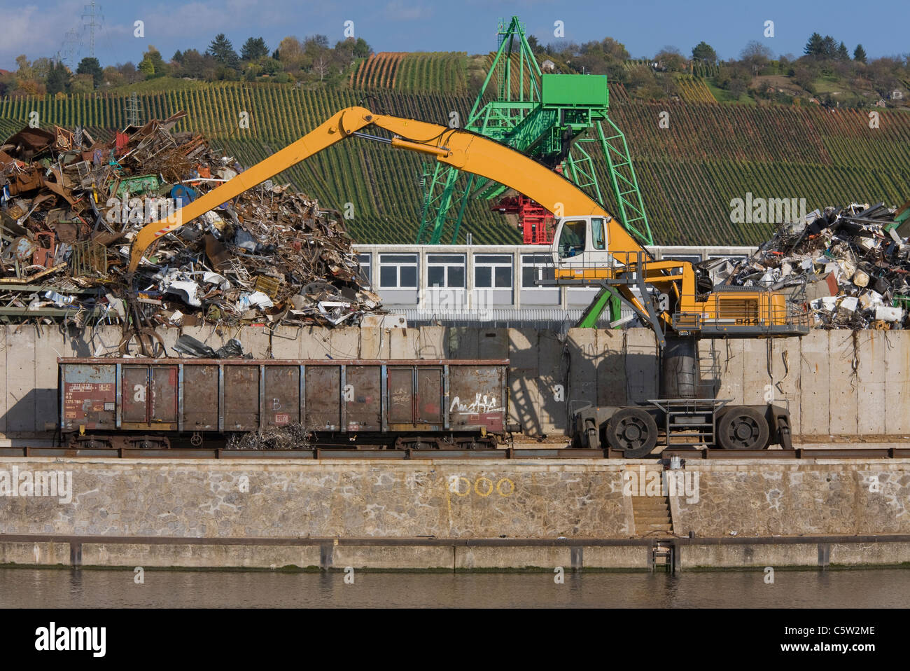 Landfill site, Shovel filling container, vineyard in background Stock ...