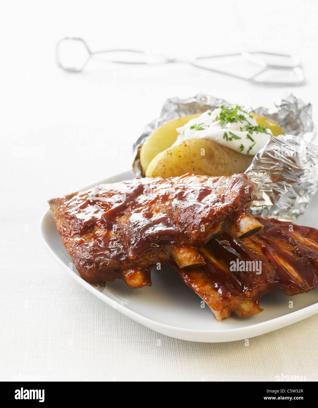 Barbecued Ribs with Baked potato on plate Stock Photo - Alamy