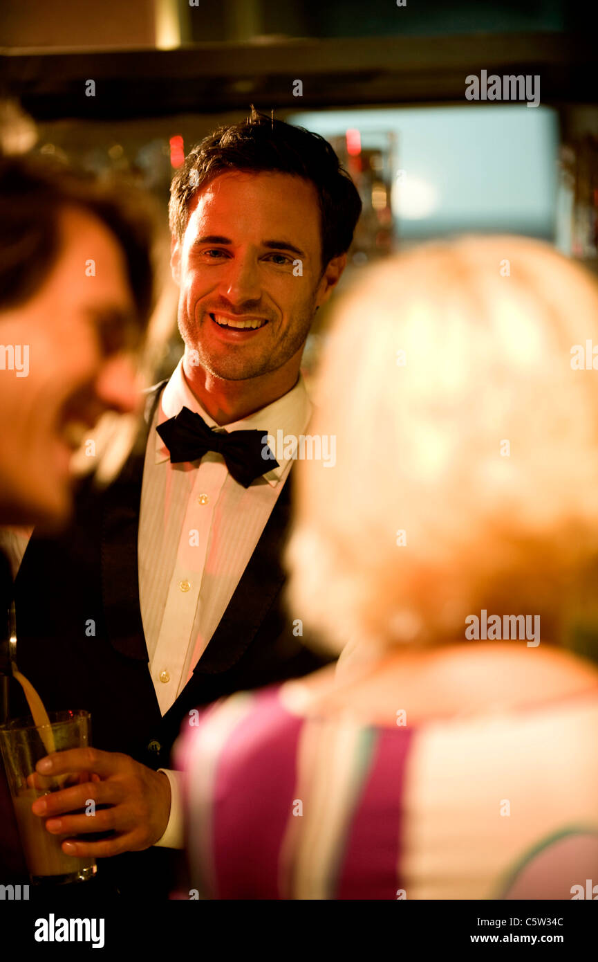 Barkeeper and guests in bar Stock Photo - Alamy