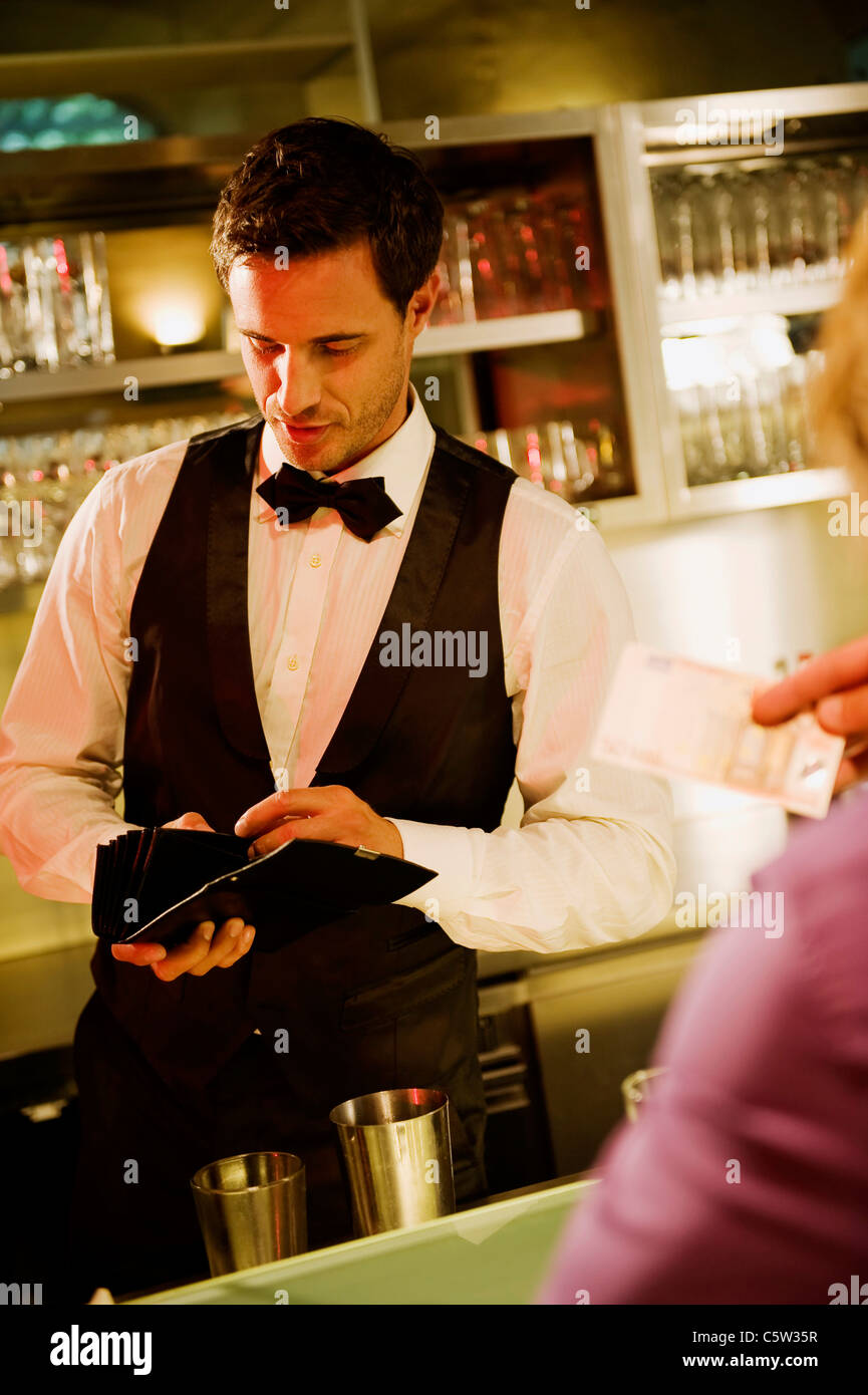 Man handing money to barkeeper Stock Photo - Alamy