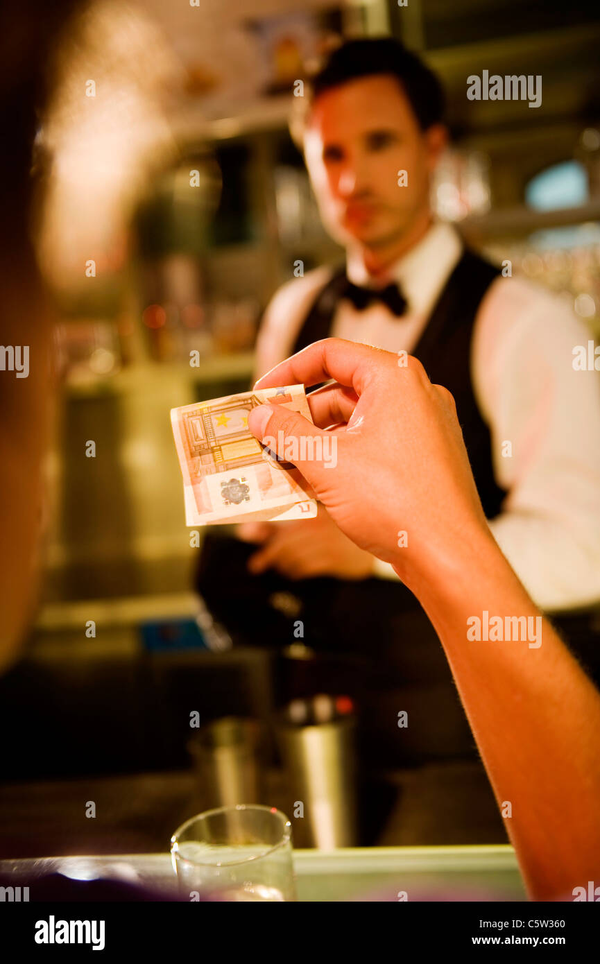 Man handing money to barkeeper Stock Photo - Alamy