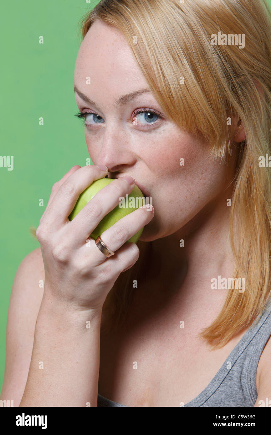Young woman biting into an apple, portrait Stock Photo - Alamy