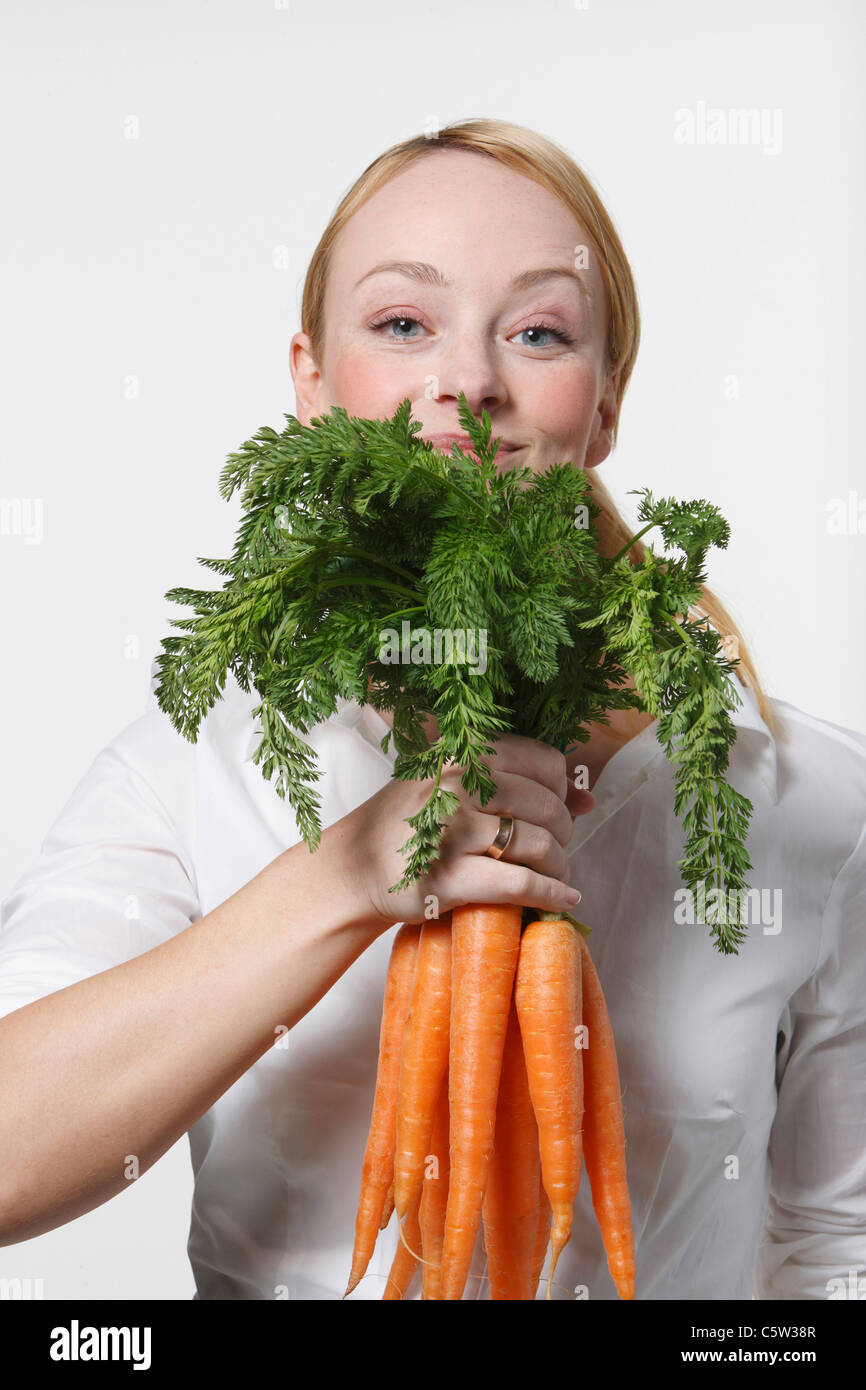 Young woman holding bunch of carrots, portrait Stock Photo - Alamy