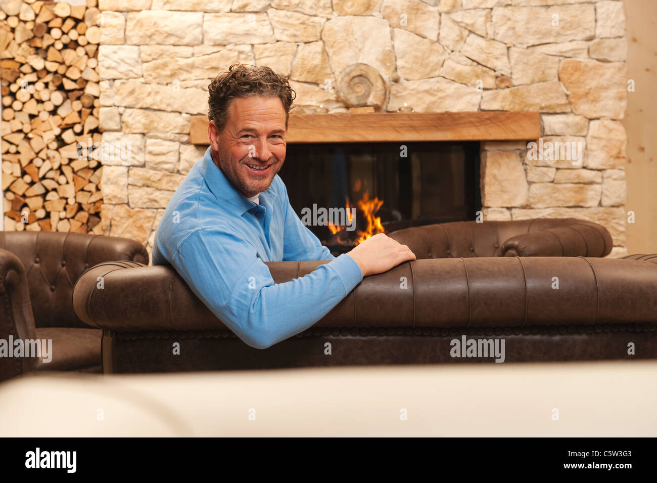 Man sitting in front of fire place, smiling, portrait Stock Photo - Alamy