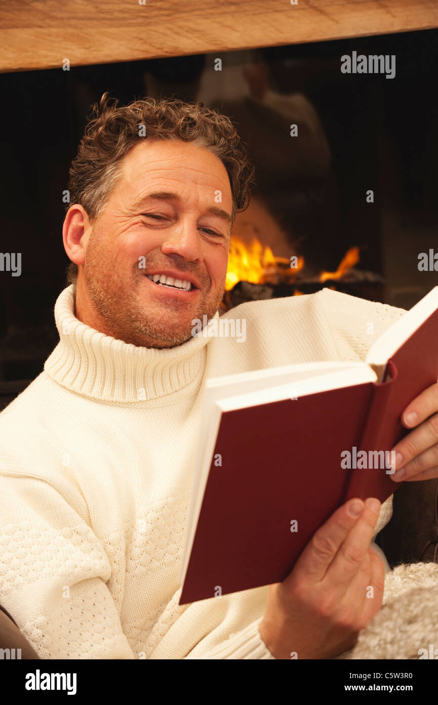 Man in front of fire place reading a book, portrait Stock Photo - Alamy