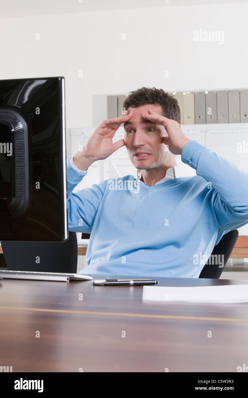 Germany, Munich, business man in office, hands on head, portrait Stock ...