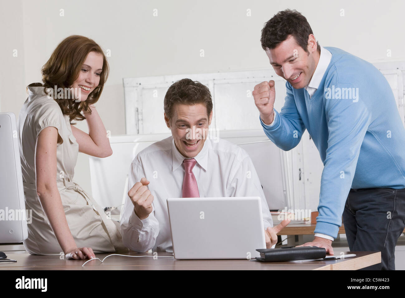 Germany, Munich, co-workers together in office, cheering Stock Photo ...