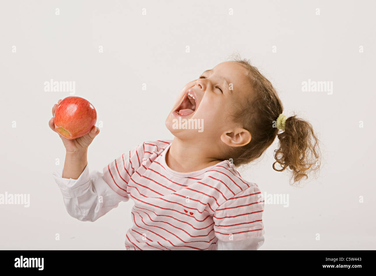 Girl (2-3) holding an apple, laughing, side view, portrait Stock Photo ...