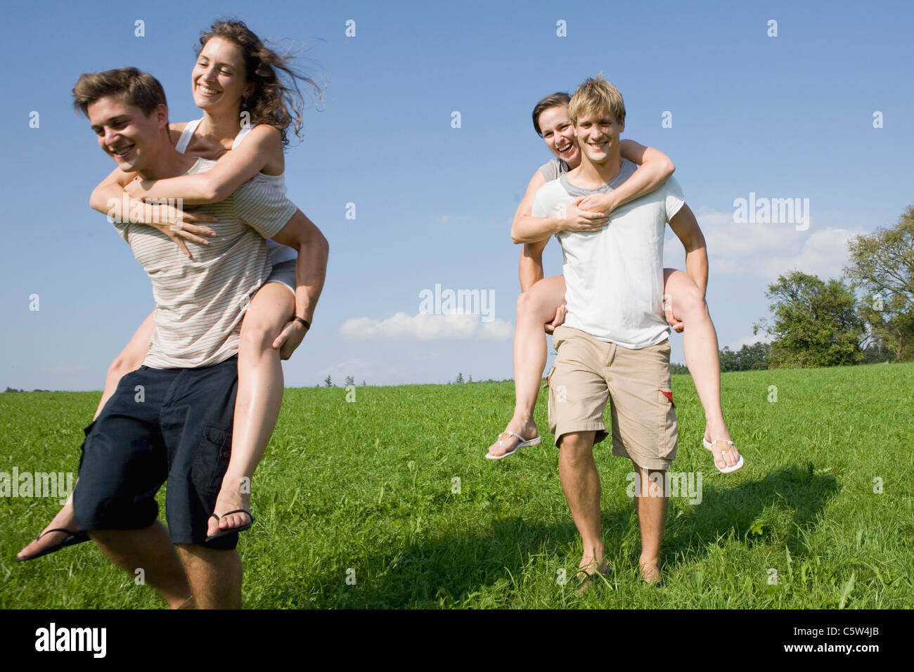 Germany, Bavaria, Young men carrying young women on back Stock Photo ...