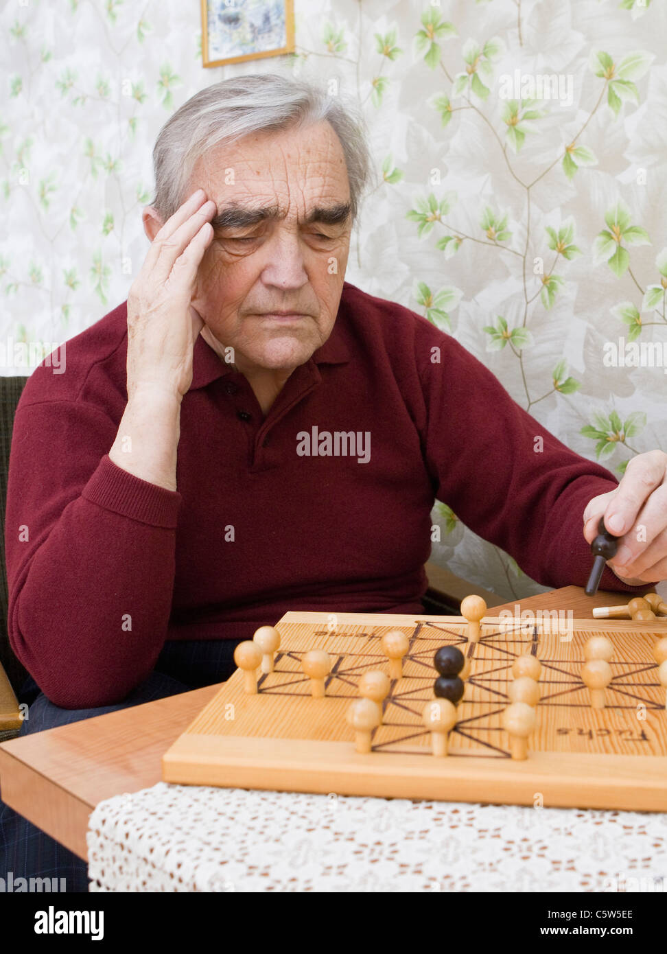 Man playing board game with head in hand Stock Photo - Alamy