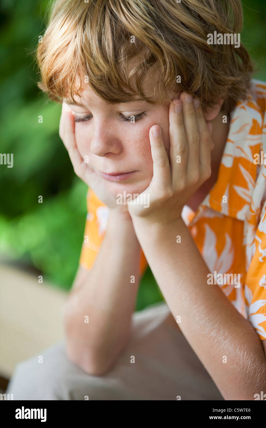 Germany, Bavaria, Teenage boy (13-14) head in hands, looking down ...