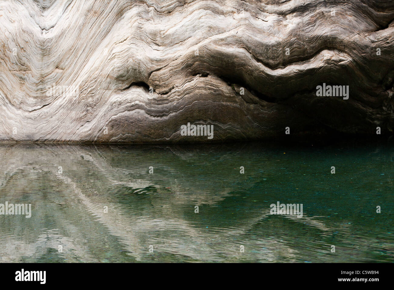 Folded layers, pattern in the rock, reflection in emerald green river ...