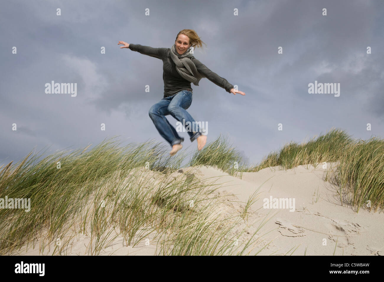 Germany, Schleswig Holstein, Woman in sand dunes, jumping Stock Photo ...