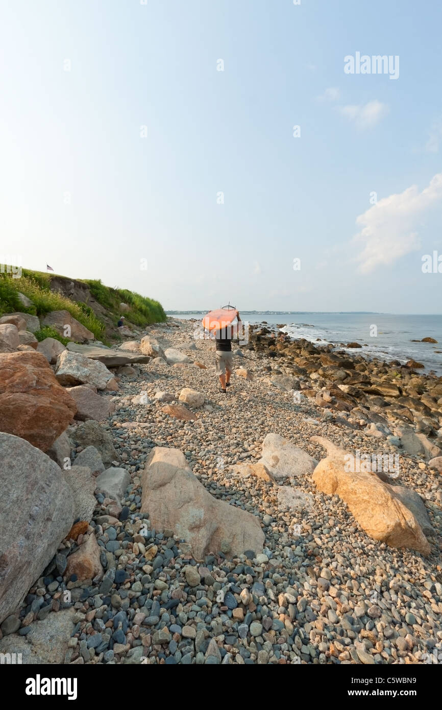 Male surfer walking down the rocky shoreline in Point Judith, Rhode ...
