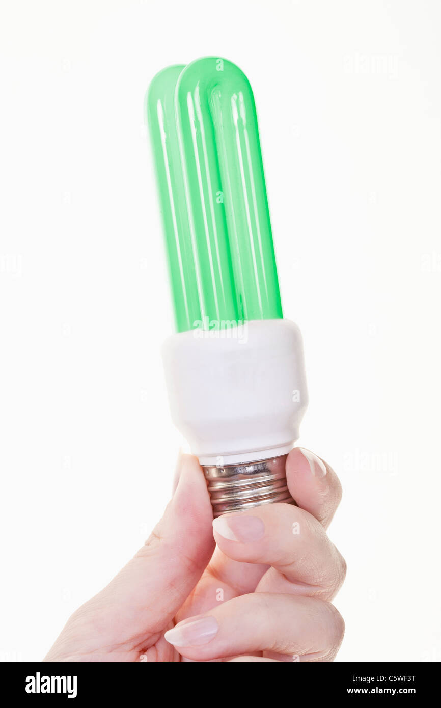 Hand of woman holding green lightbulb against white background, close ...