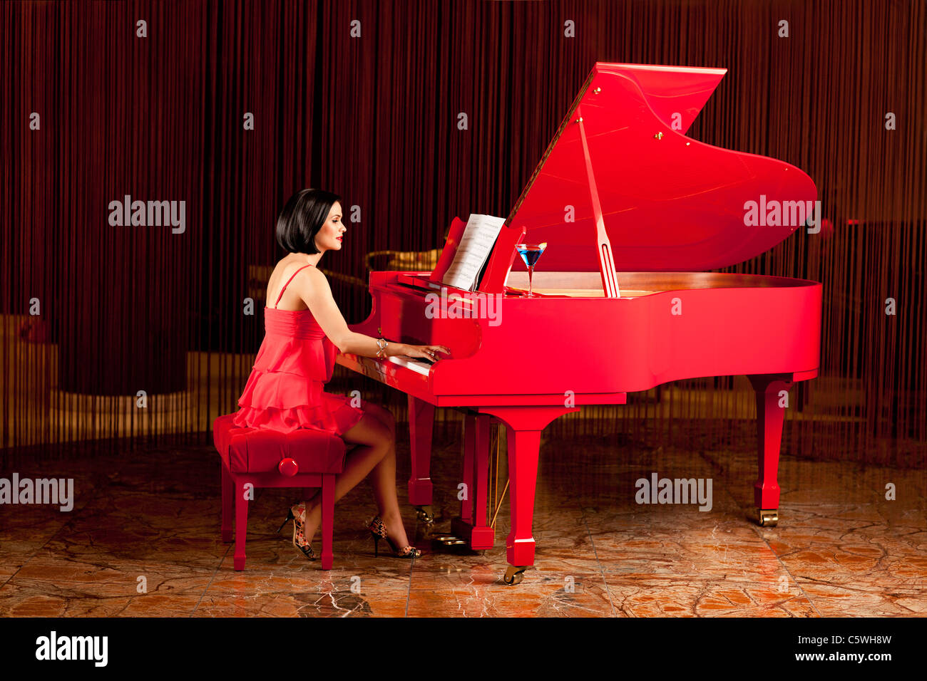 elegant brunette woman in red dress playing piano Stock Photo - Alamy