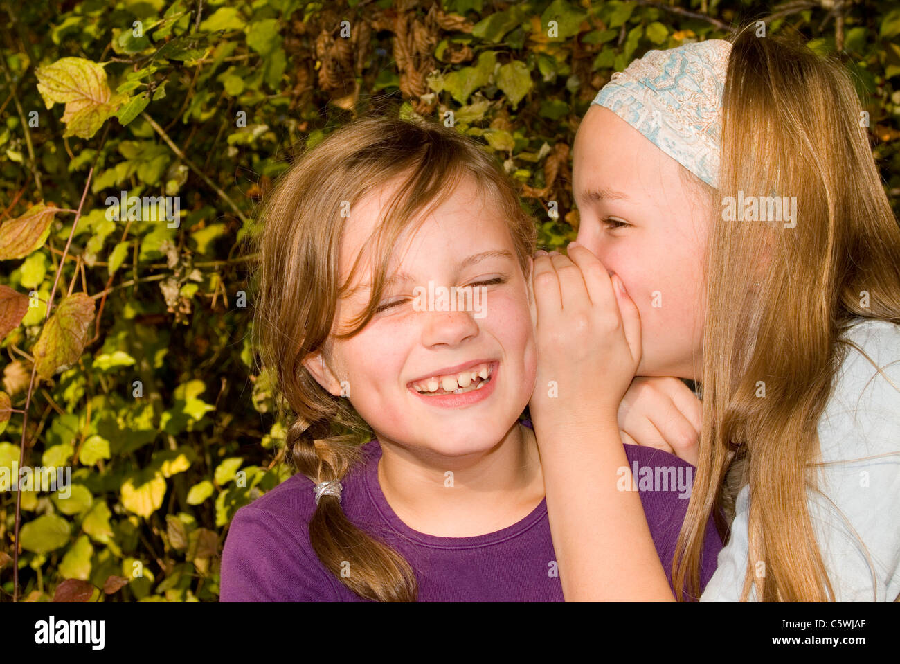 Girl whispering in friends ear hi-res stock photography and images - Alamy