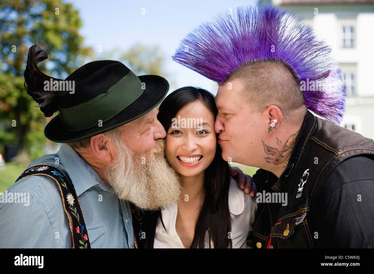 Germany, Bavaria, Upper Bavaria, Two men kissing Asian woman on cheek ...