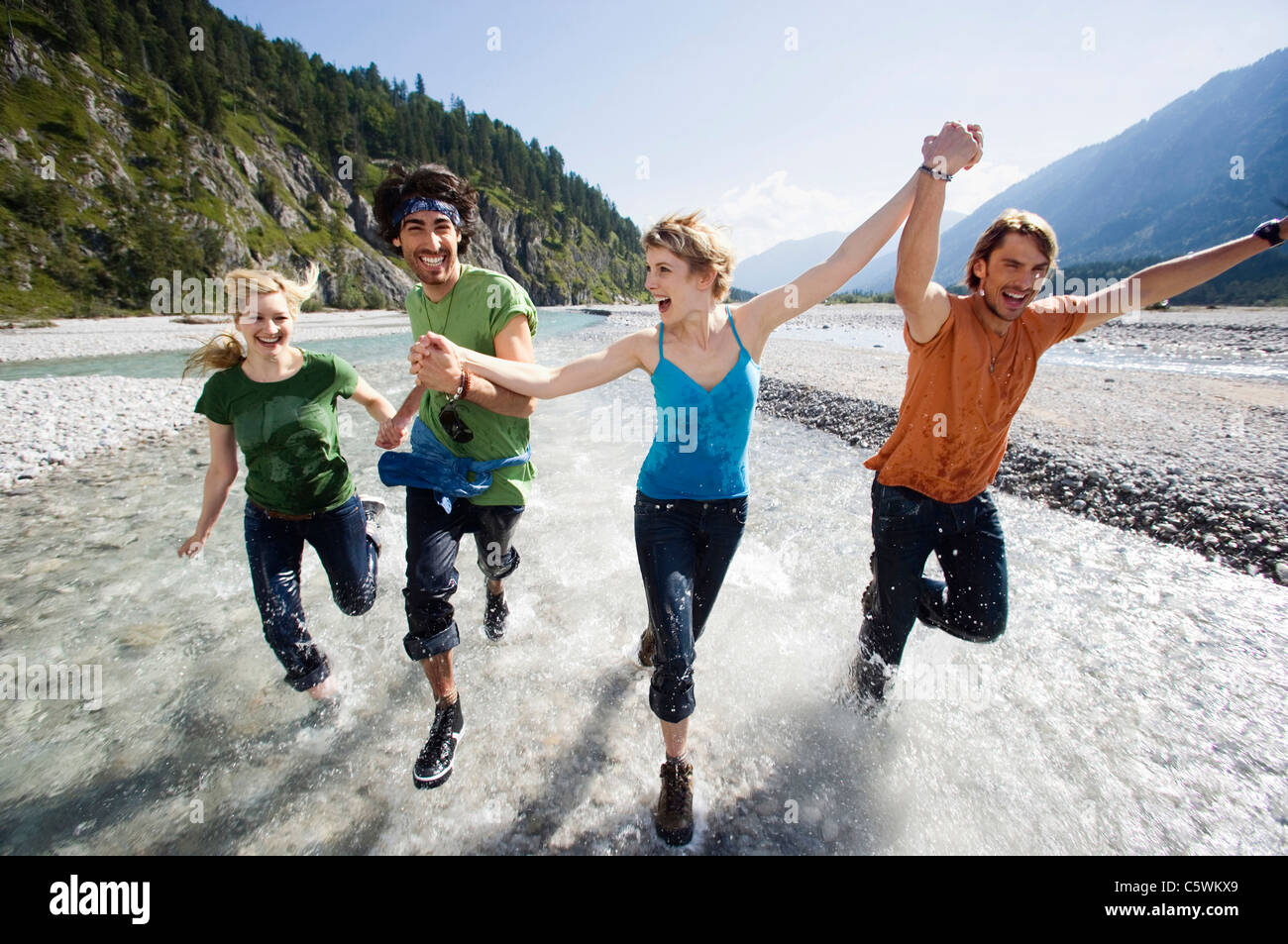 Germany, Bavaria, TÃ¶lzer Land, Young people running through river ...