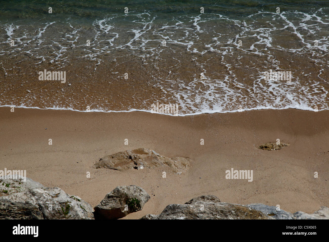 A sandy beach with a mild wave covering most of the sand Stock Photo ...