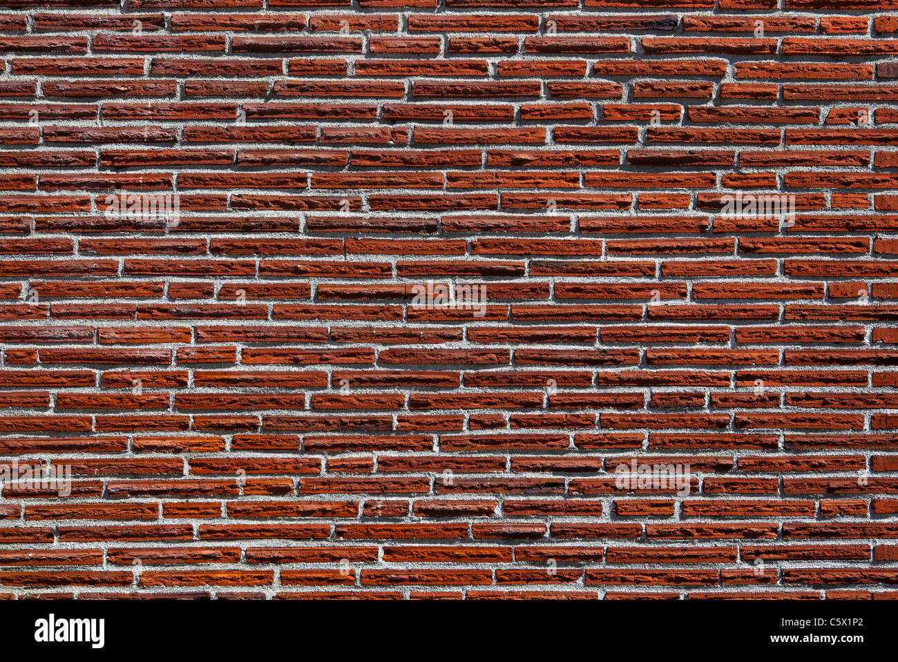 Sun lit skinny or thin long red brick wall Stock Photo - Alamy