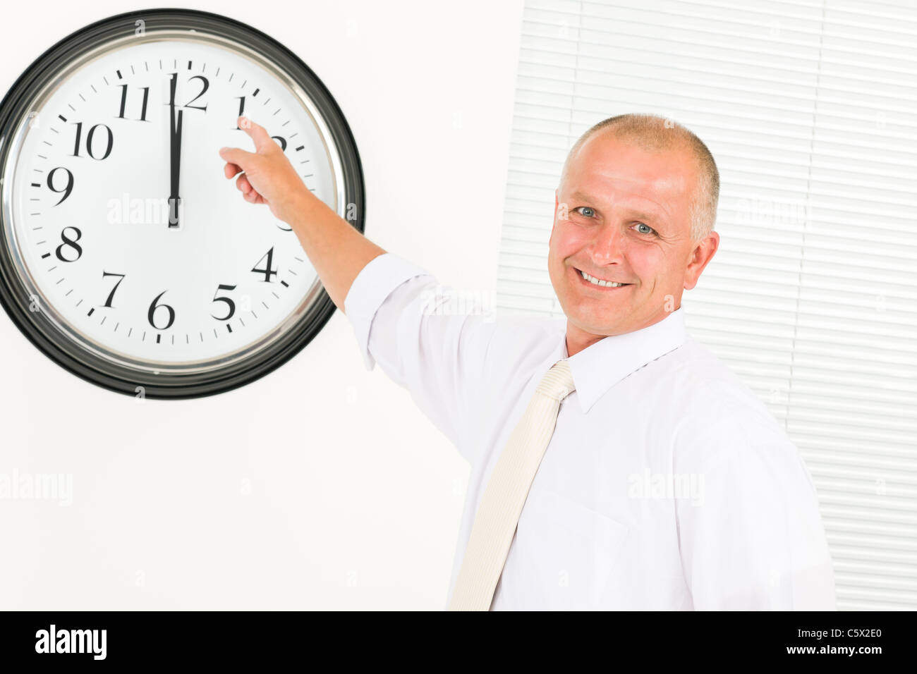 Punctual businessman senior handsome pointing at clock portrait Stock ...