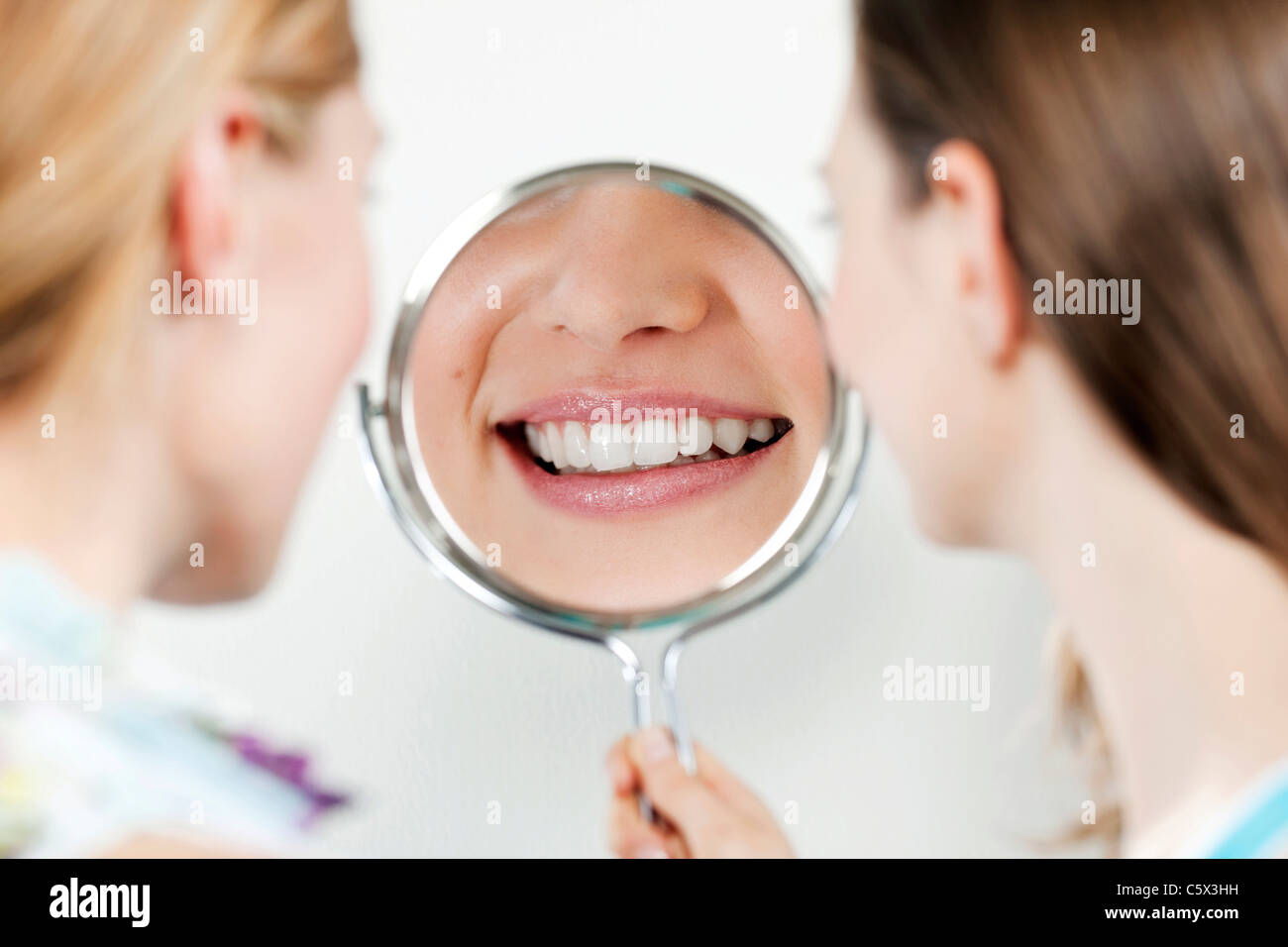 Young women looking into mirror Stock Photo - Alamy