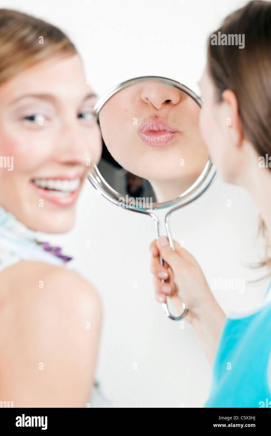 Young women looking into mirror Stock Photo - Alamy