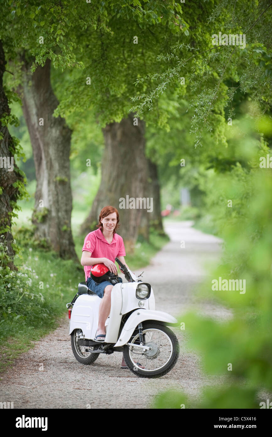 Germany, Bavaria, Young man on moped, smiling, portrait Stock Photo - Alamy