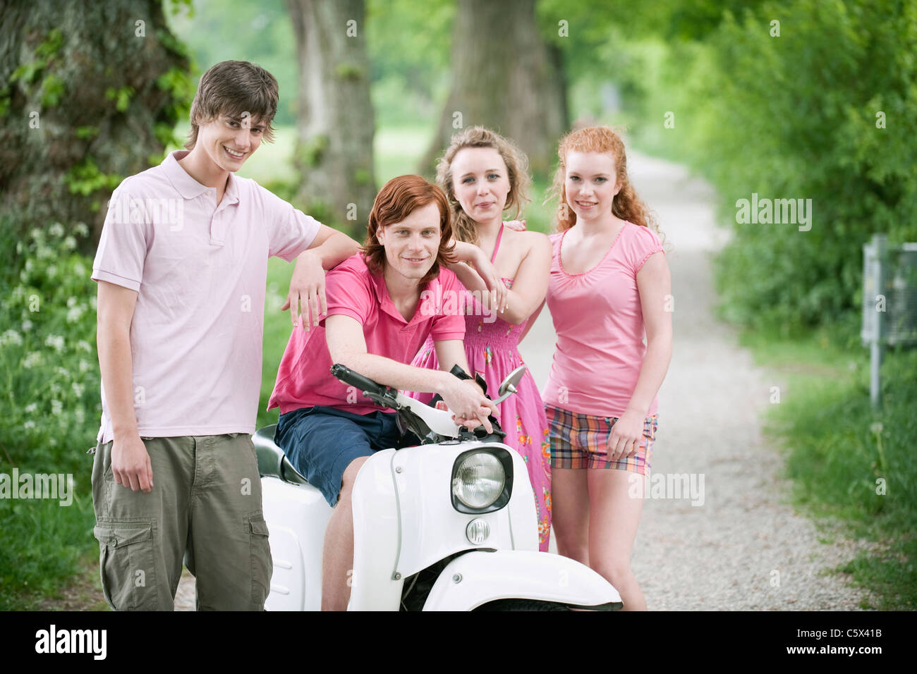 Germany, Bavaria, Four friends standing by moped, portrait Stock Photo ...