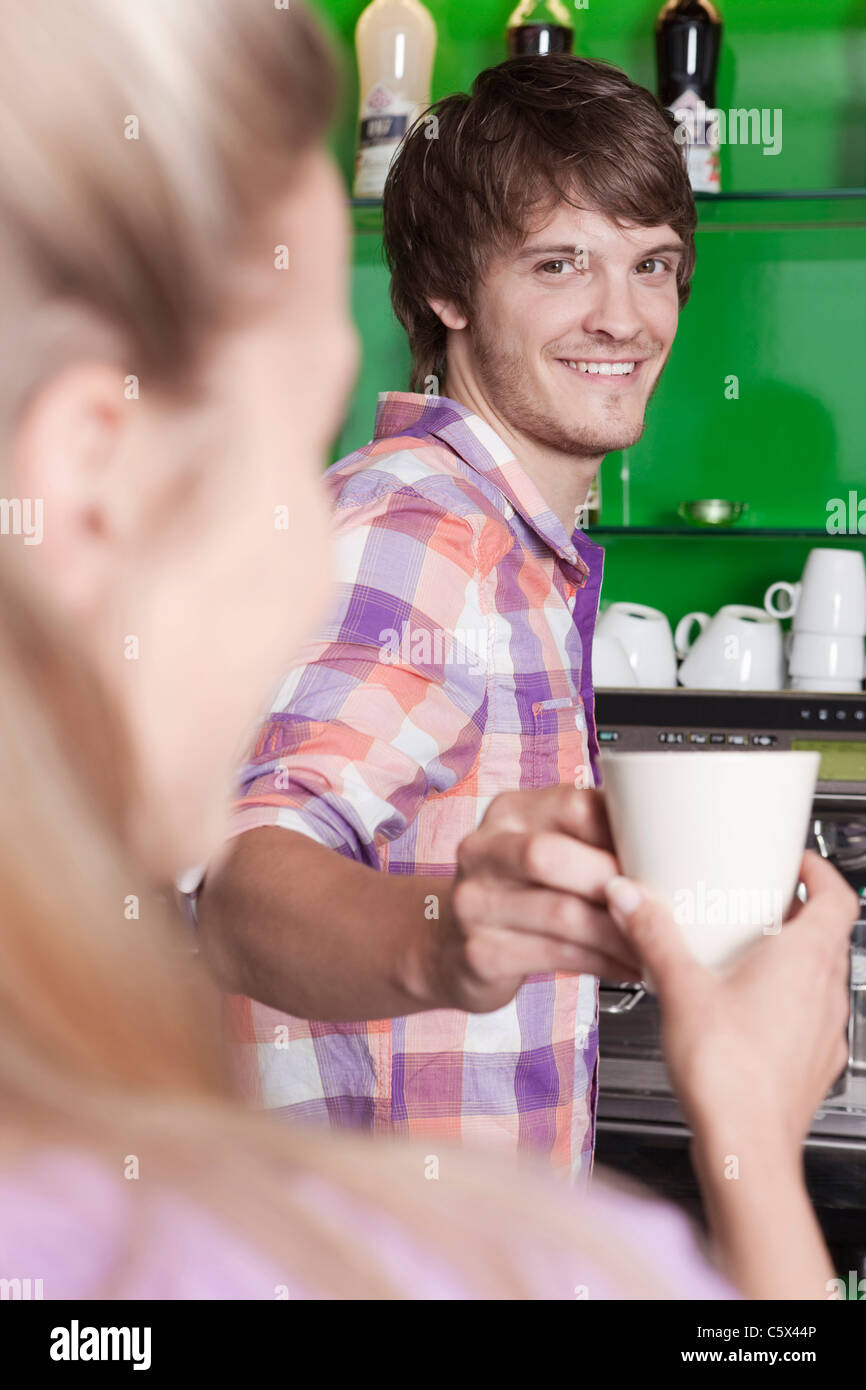 Germany, Cologne, Man handing coffee over counter Stock Photo - Alamy
