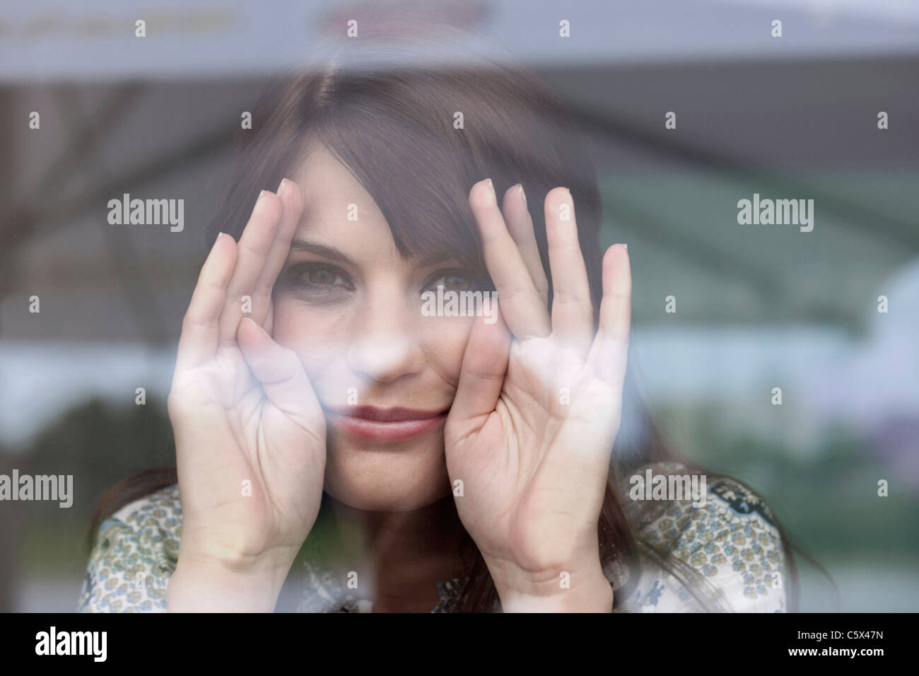Germany, Cologne, Woman looking through window, portrait Stock Photo ...