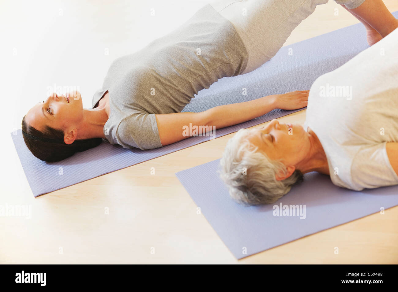 Two women arching back on gym mat Stock Photo - Alamy