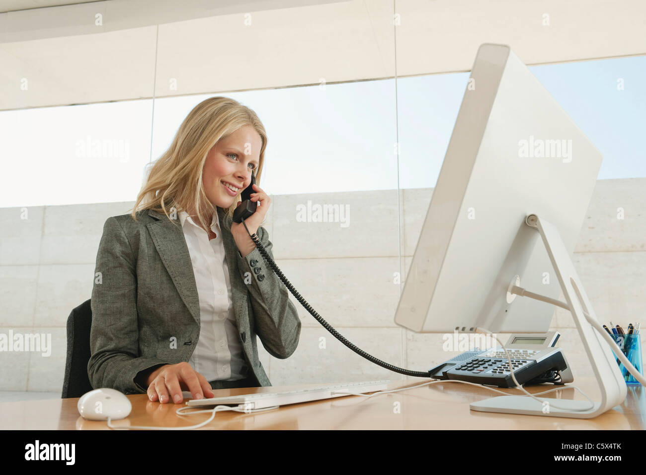 Young woman in office using phone Stock Photo - Alamy